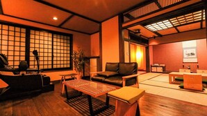 Um quarto tradicional em estilo japonês, com tatames, uma mesa baixa, um sofá e uma escrivaninha com cadeira.