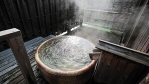 Uma banheira de hidromassagem com jatos de água, rodeada por um deck de madeira e uma cerca de madeira.