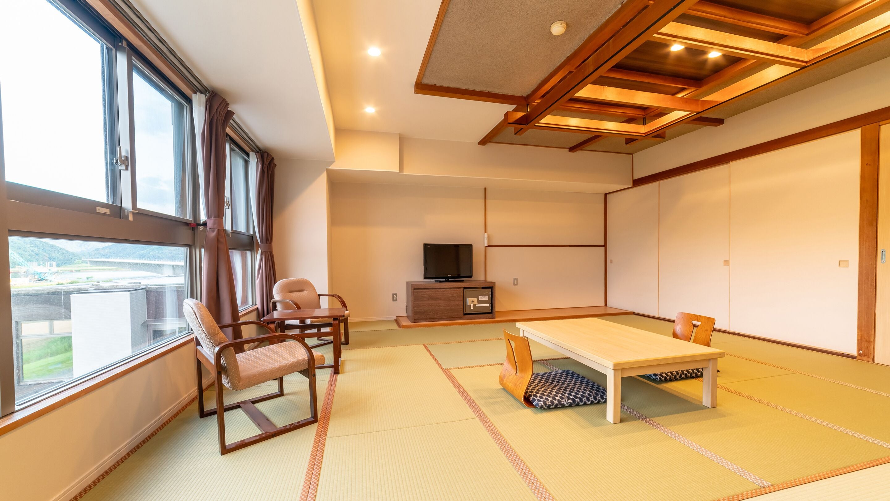 Quarto tradicional japonês com tatames, uma mesa baixa e uma televisão sobre um móvel.