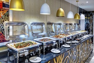 Buffet com diversas estações de serviço, cada uma com uma variedade de pratos.