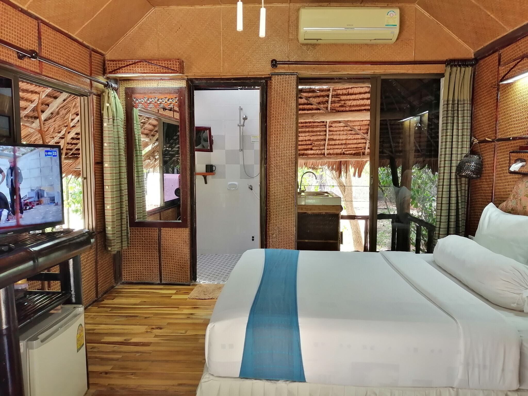 Um quarto com uma cama, televisão e um pequeno frigorífico.