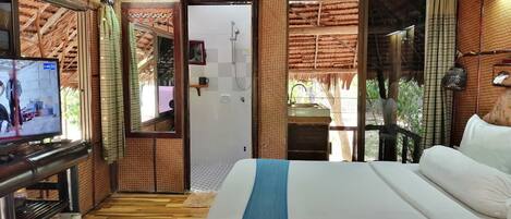 Um quarto com uma cama, televisão e um pequeno frigorífico.