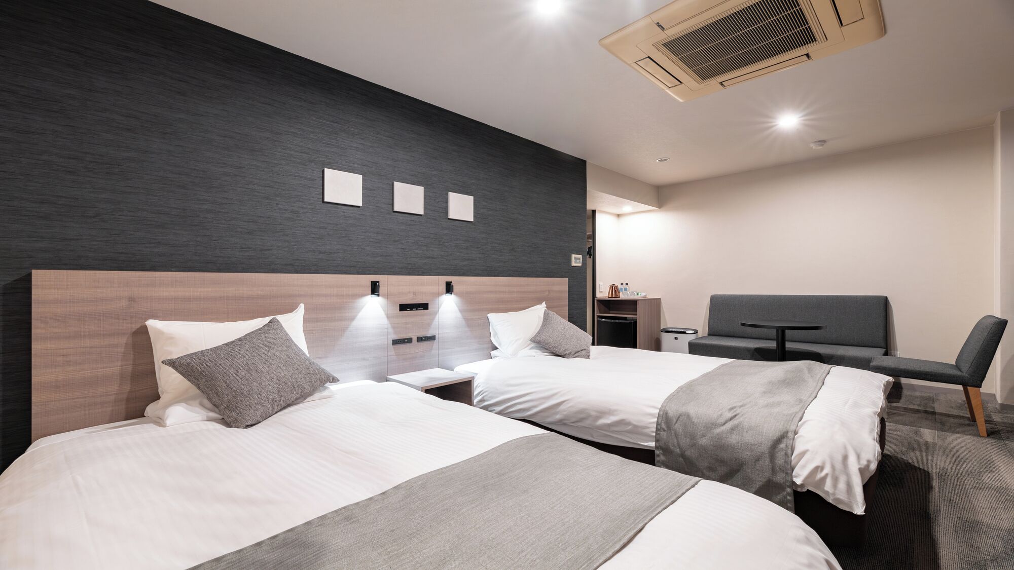 Quarto de hotel moderno com duas camas, uma TV, uma escrivaninha e uma cadeira.