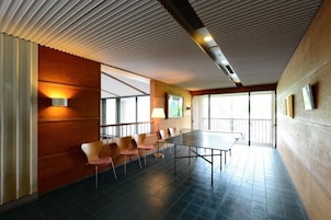 Uma sala de conferências com uma mesa comprida e cadeiras, janelas amplas e teto com design em relevo.