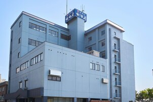 Um edifício de vários andares com fachada plana, diversas janelas e uma placa com caracteres japoneses.