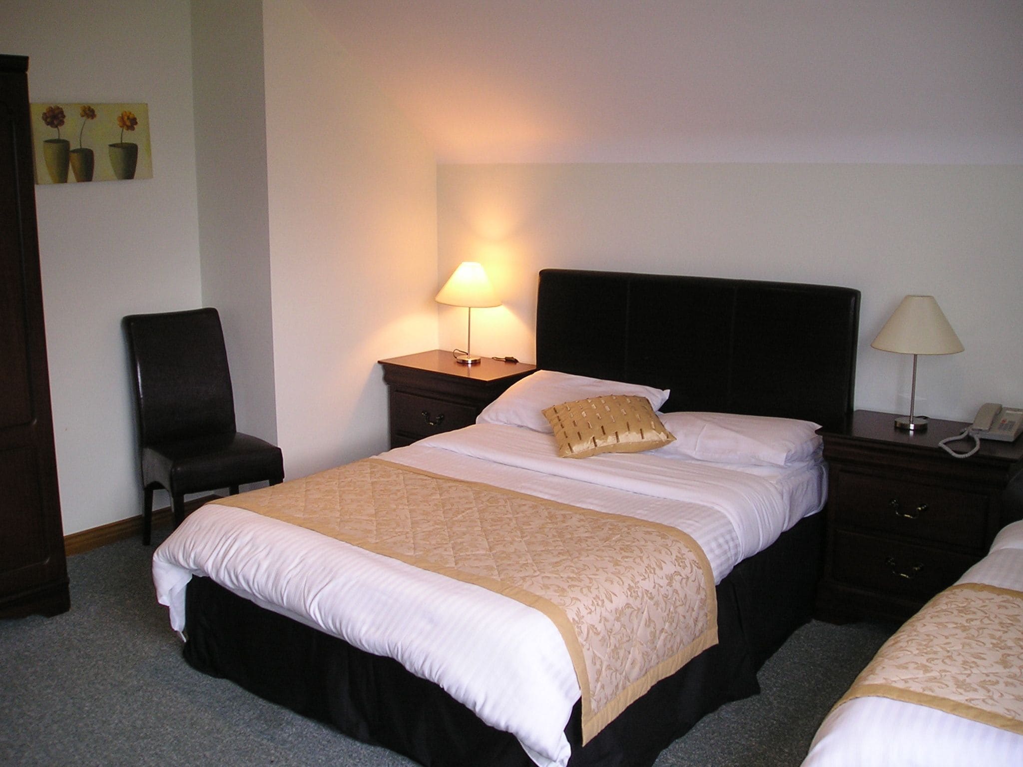 Quarto de hotel com uma cama, duas mesas de cabeceira, uma cadeira e um abajur.
