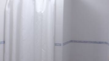 Um banheiro com cortina de chuveiro branca, vaso sanitário e pia.