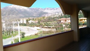Uma varanda com vista para uma montanha, uma estrada e edifícios.