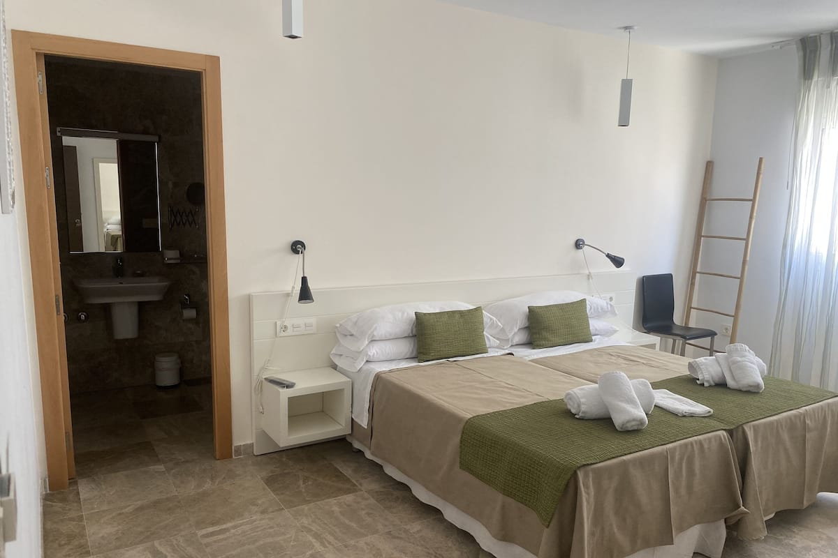 Quarto de hotel com duas camas, banheiro e espelho.