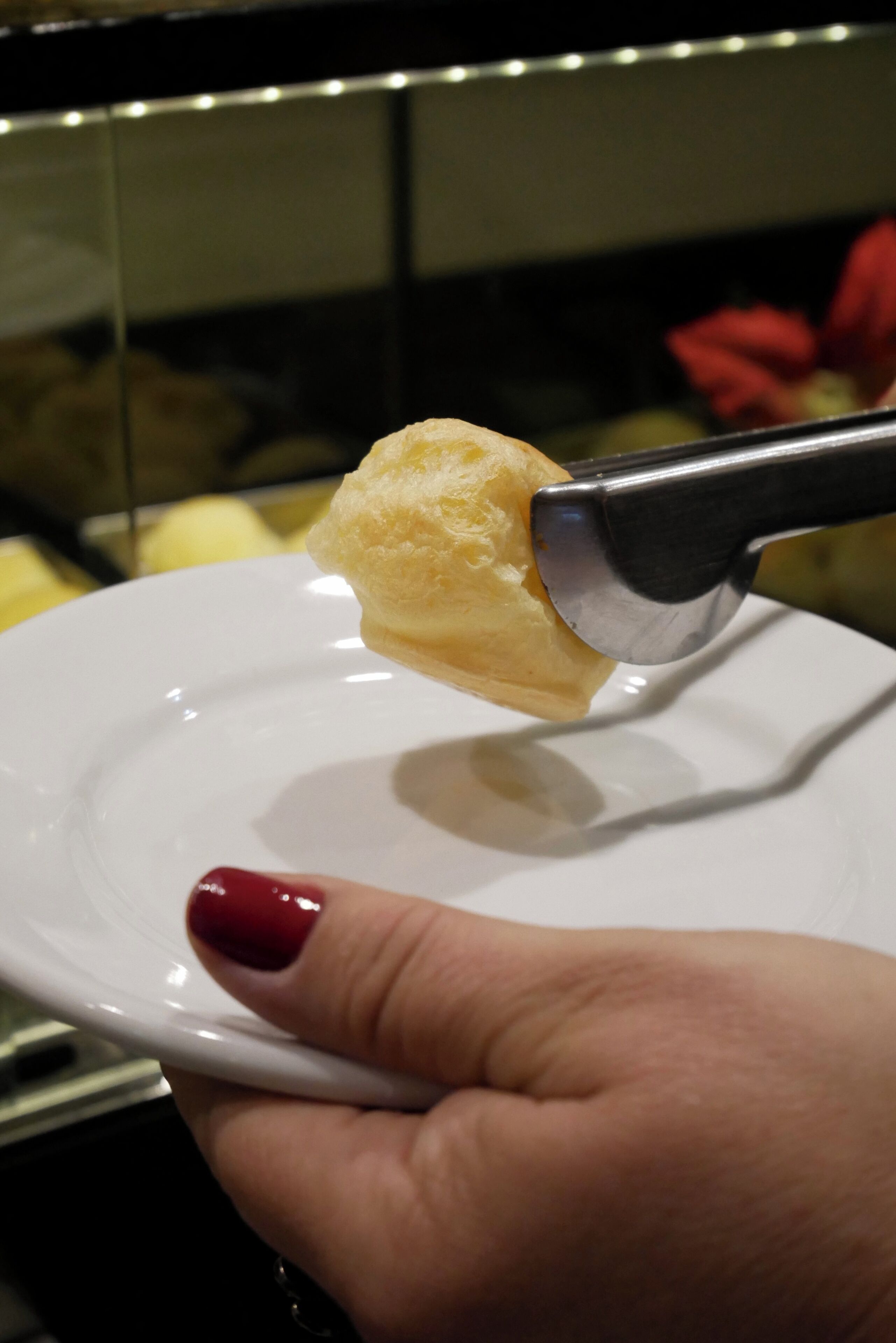 Uma mão segurando um prato branco com um pedaço de comida.