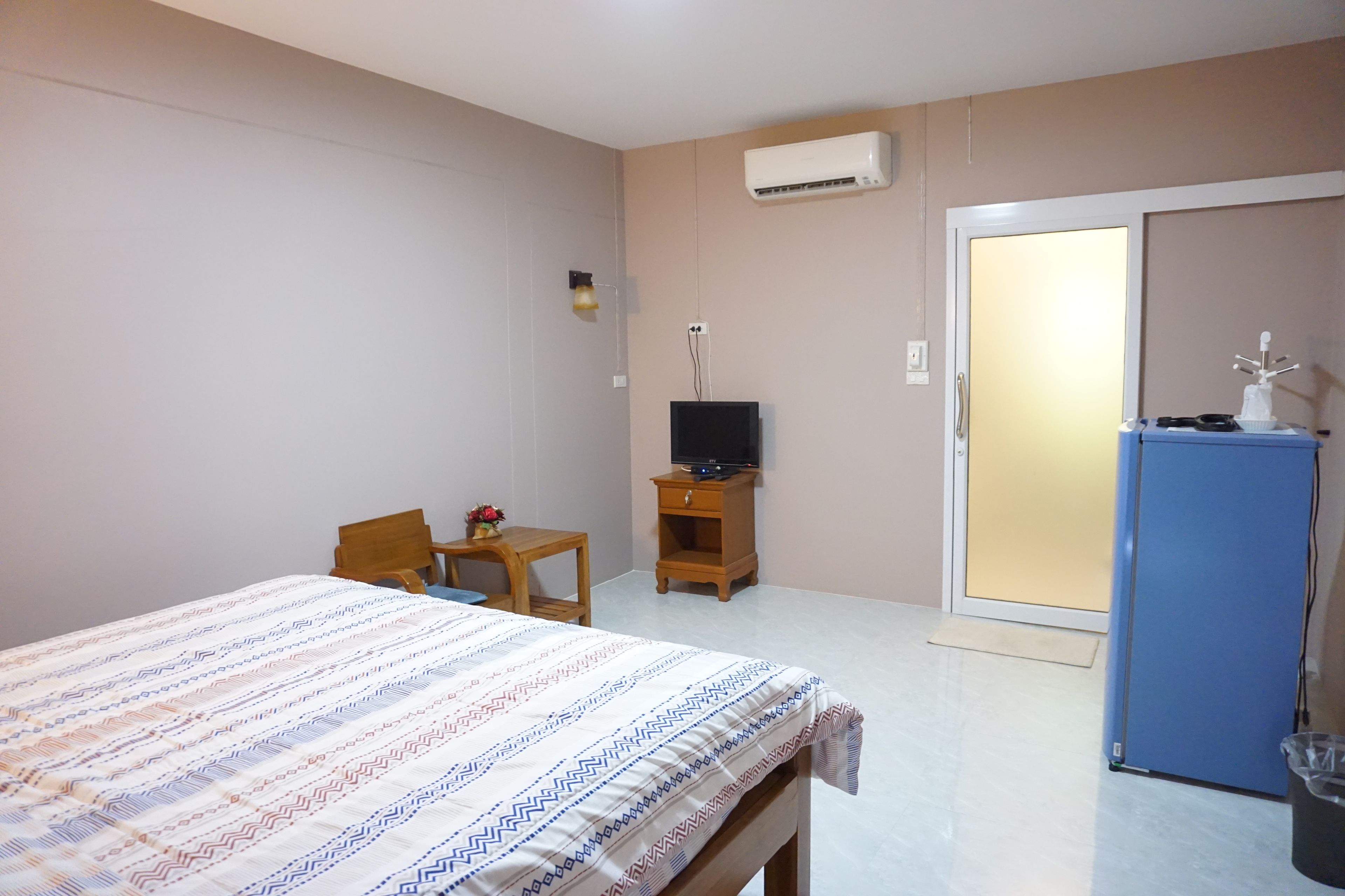 Quarto de hotel com cama, escrivaninha, televisão e ar condicionado.