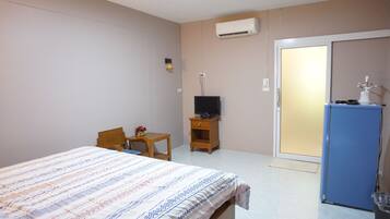 Quarto de hotel com cama, escrivaninha, televisão e ar condicionado.