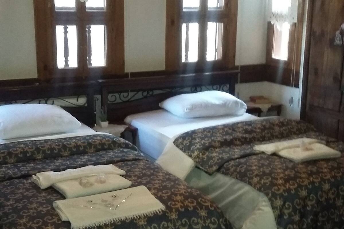 Quarto de hotel com duas camas, piso de madeira e um espelho grande.