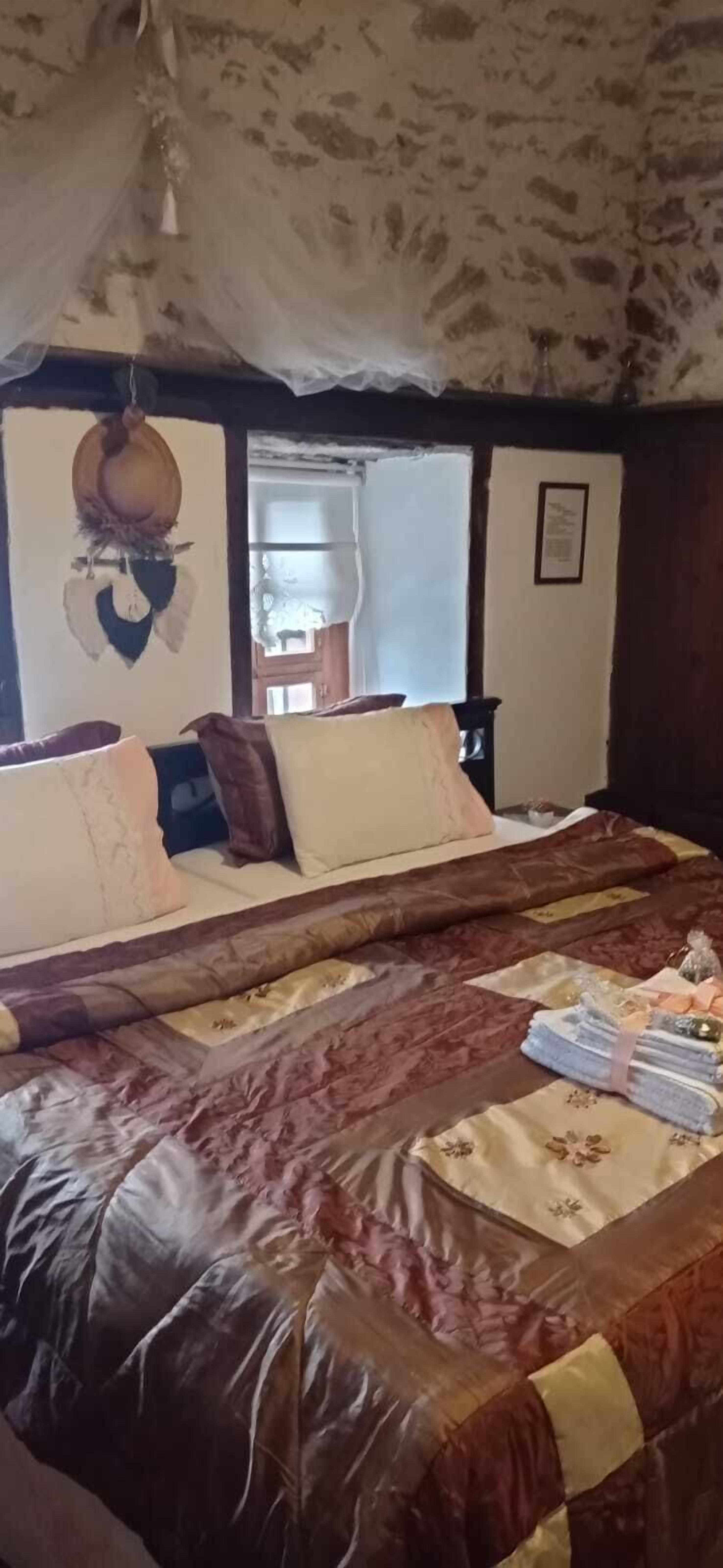 Uma cama com colcha e travesseiros, uma decoração pendurada e um quadro na parede.