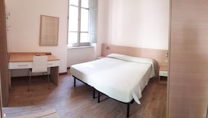 Um quarto com uma cama, uma escrivaninha e uma cadeira.