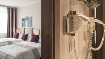 Quarto de hotel com cama, espelho e secador de cabelo na parede.