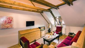Um quarto estilo loft acolhedor, com vigas de madeira aparente, um banco de madeira, um sofá vermelho e uma pequena mesa com flores.
