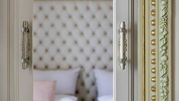 Quarto com cabeceira estofada, cama com roupa de cama branca e painel decorativo na parede.