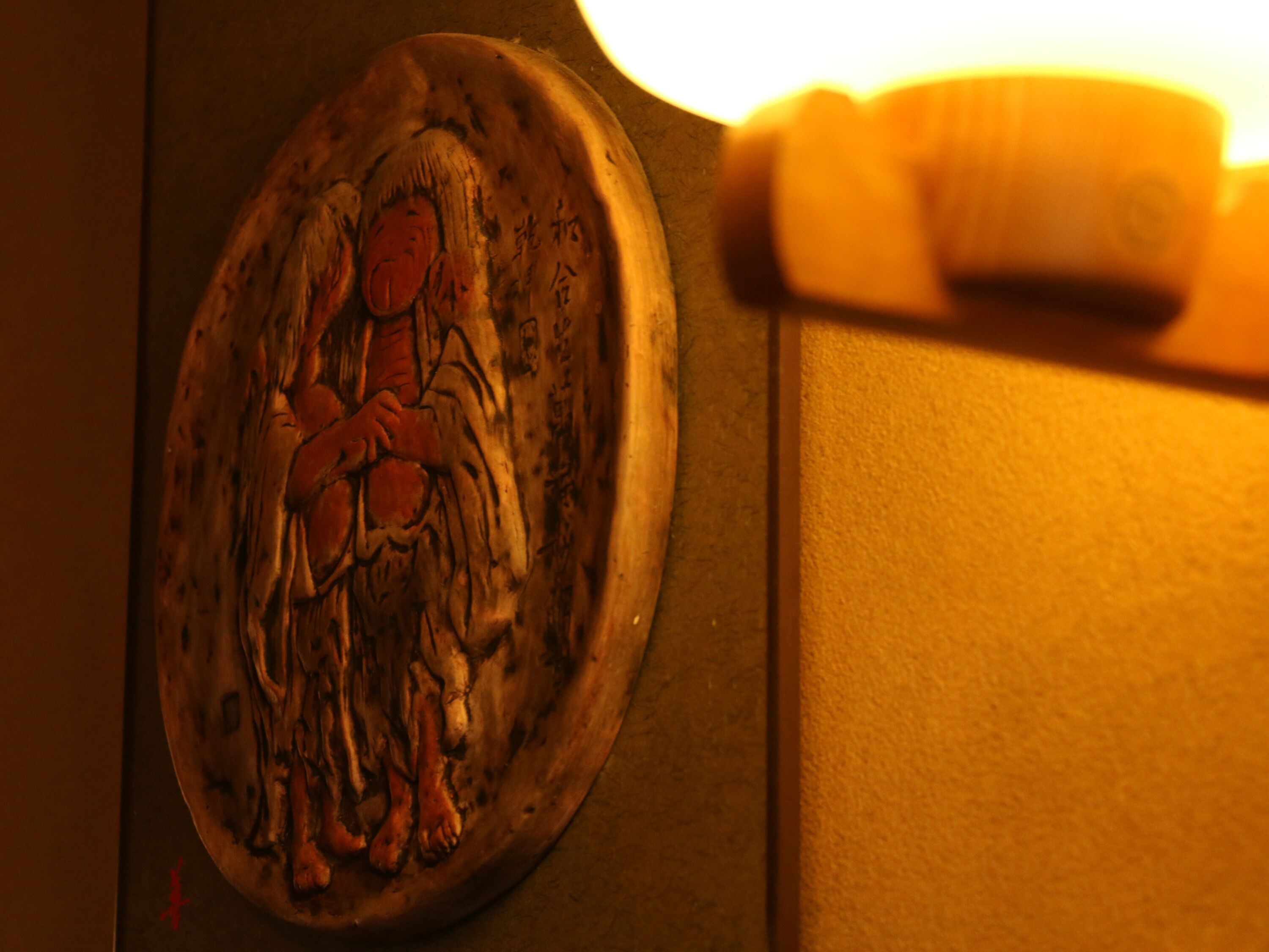 Parede com relevo circular retratando uma figura segurando uma criança.