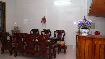 Quarto com um banco de madeira, uma pequena mesa e um armário com um vaso de flores.
