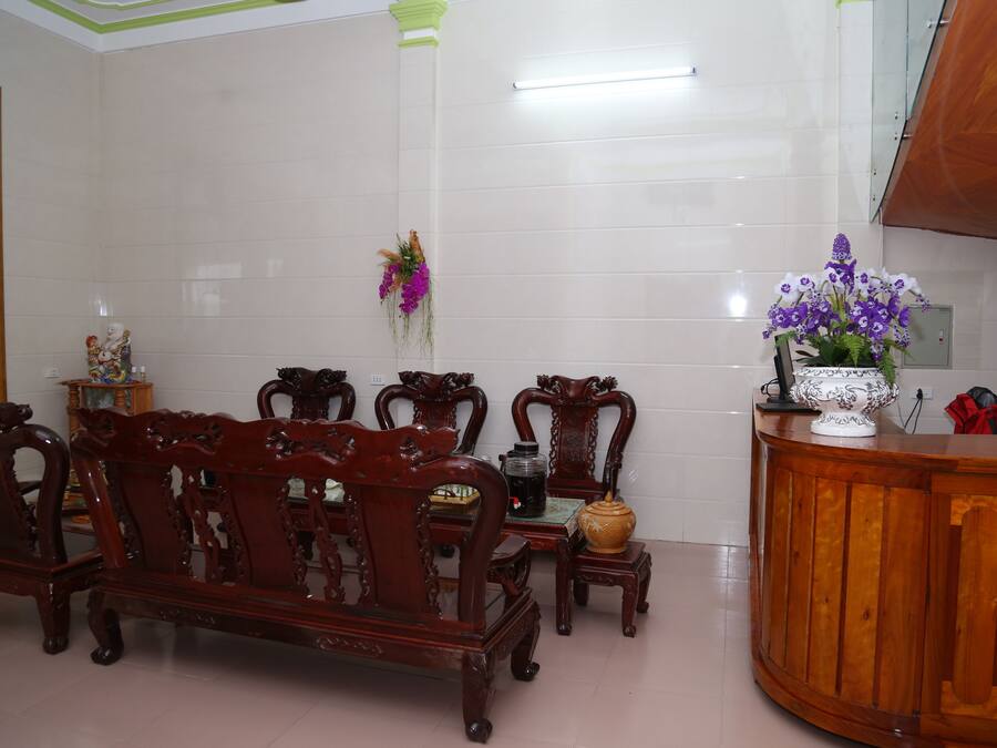 Quarto com um banco de madeira, uma pequena mesa e um armário com um vaso de flores.