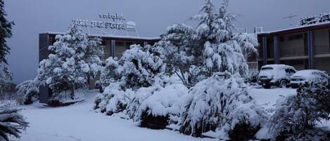 Um edifício com uma placa que diz 'SANTA FE', árvores e arbustos cobertos de neve.