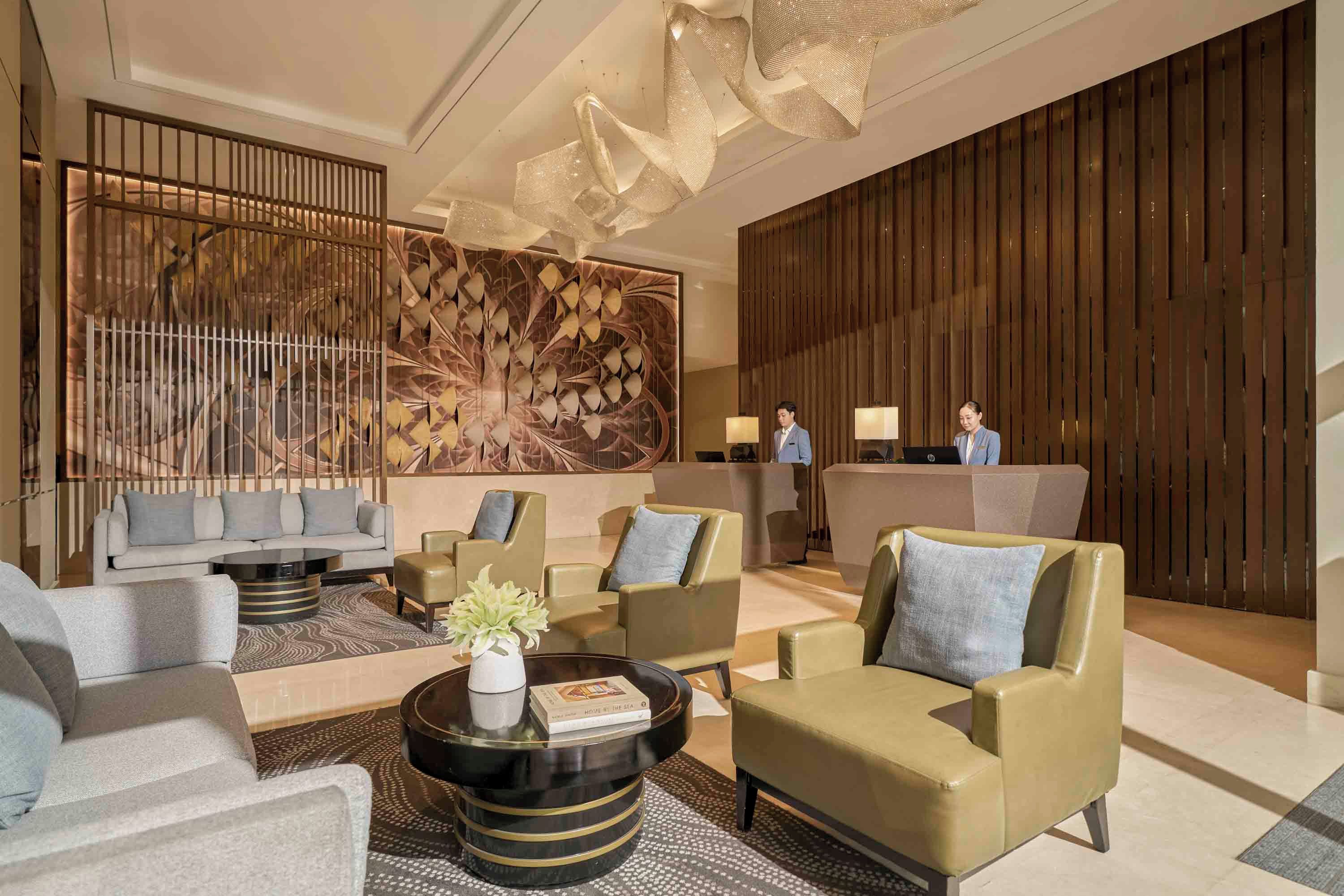 Um lobby moderno com balcão de recepção, área de estar e painéis decorativos na parede.