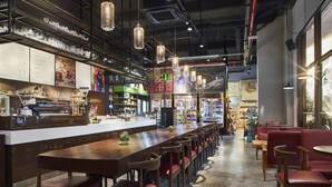 Uma área de bar com um balcão comprido, vários bancos e luminárias pendentes.