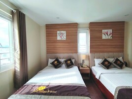 Quarto de hotel com duas camas, cabeceiras de madeira e obras de arte nas paredes.