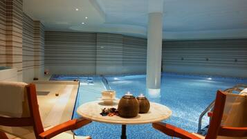 Uma área interna de piscina moderna, com espaço para sentar, uma mesa com comodidades e vista para a piscina.