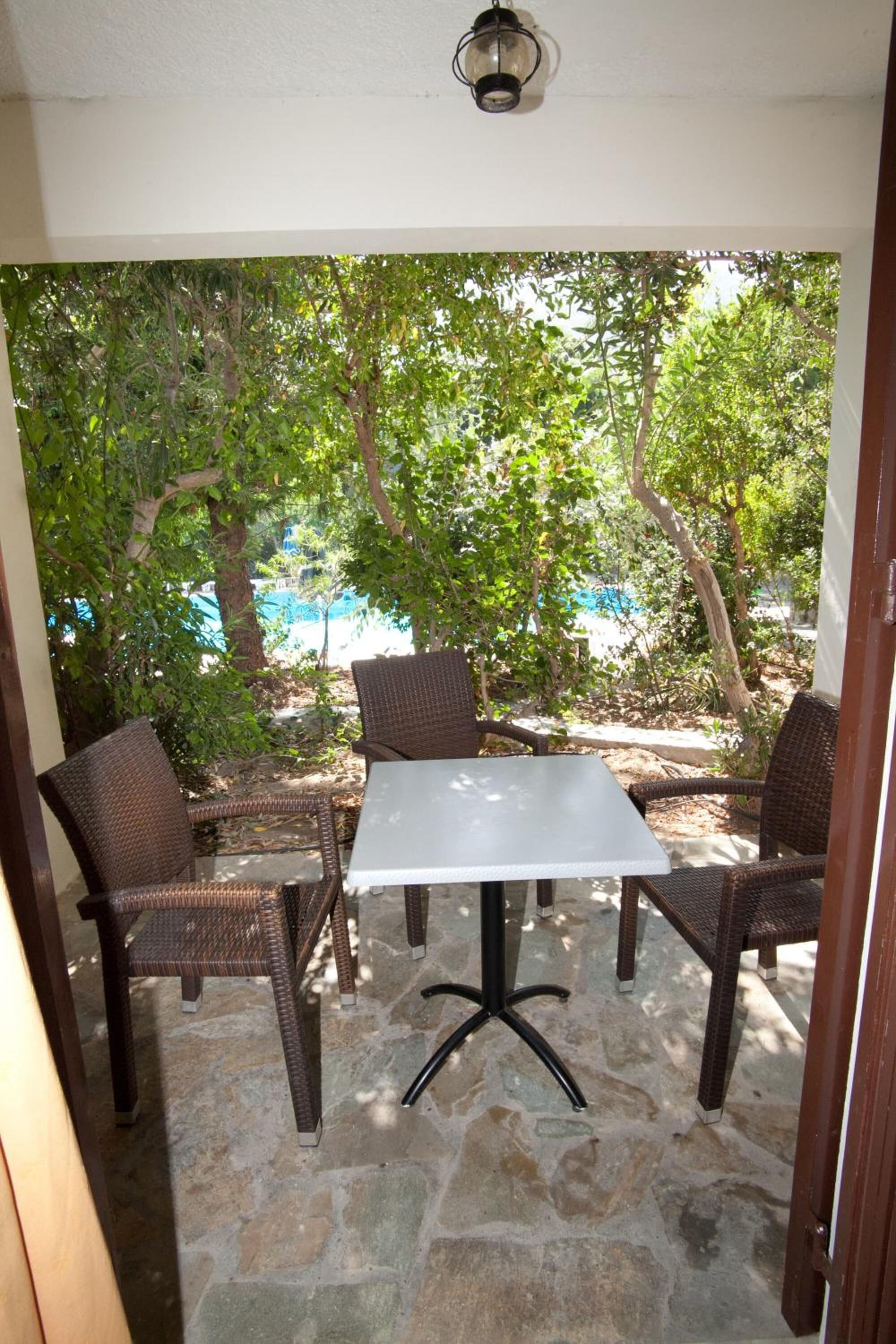 Um pátio com chão de pedra, móveis de vime e vista para uma piscina.