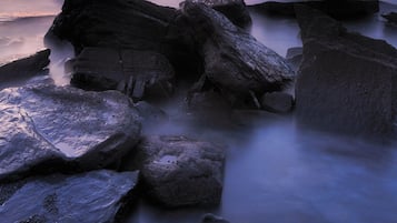 Uma costa rochosa com grandes pedras e águas calmas.