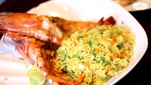 Um prato de arroz frito com legumes e um camarão grande.