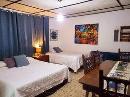 Quarto de hotel com duas camas, uma mesa de jantar e um quadro na parede.