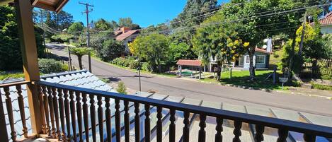 Varanda com vista para uma rua residencial, casas e vegetação.