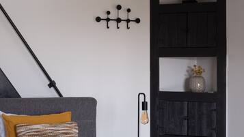 Quarto moderno com cama, mesa de cabeceira, luminária de parede e prateleira decorativa com um vaso e figuras.