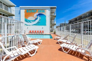 Uma área de piscina com cadeiras de descanso brancas e a placa Surf Inn.
