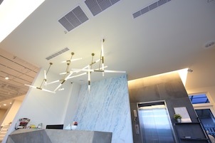 Decoração moderna com parede de mármore, balcão de recepção e luminária pendente exclusiva no teto.