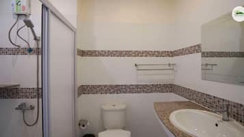 Uma casa de banho com chuveiro, sanita e lavatório.