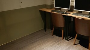 Um pequeno escritório com dois monitores de computador, teclado e uma cadeira.
