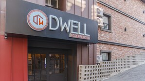 Entrada de hotel com uma placa indicando "DWELL Cozy Life-Hotel".