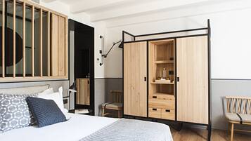 Um quarto com cama, guarda-roupa de madeira, cadeira e mesa de cabeceira.