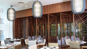 Uma sala de jantar moderna com divisórias de madeira, mesas redondas e cadeiras.