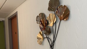 Um corredor com parede texturizada e uma peça de arte decorativa em metal.