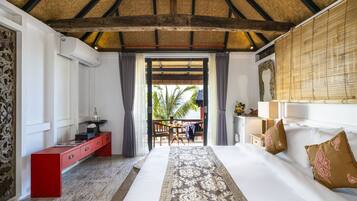 Quarto com uma cama, uma mesinha de console vermelha, uma janela grande e vista para o exterior.