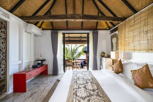 Quarto com uma cama, uma mesinha de console vermelha, uma janela grande e vista para o exterior.
