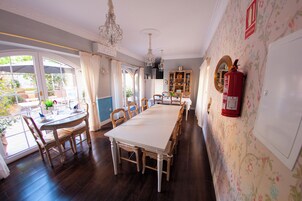 Uma área de refeições com uma mesa comprida, cadeiras e um candelabro.