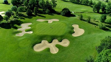 Vista aérea de um campo de golfe com bunkers de areia e árvores.