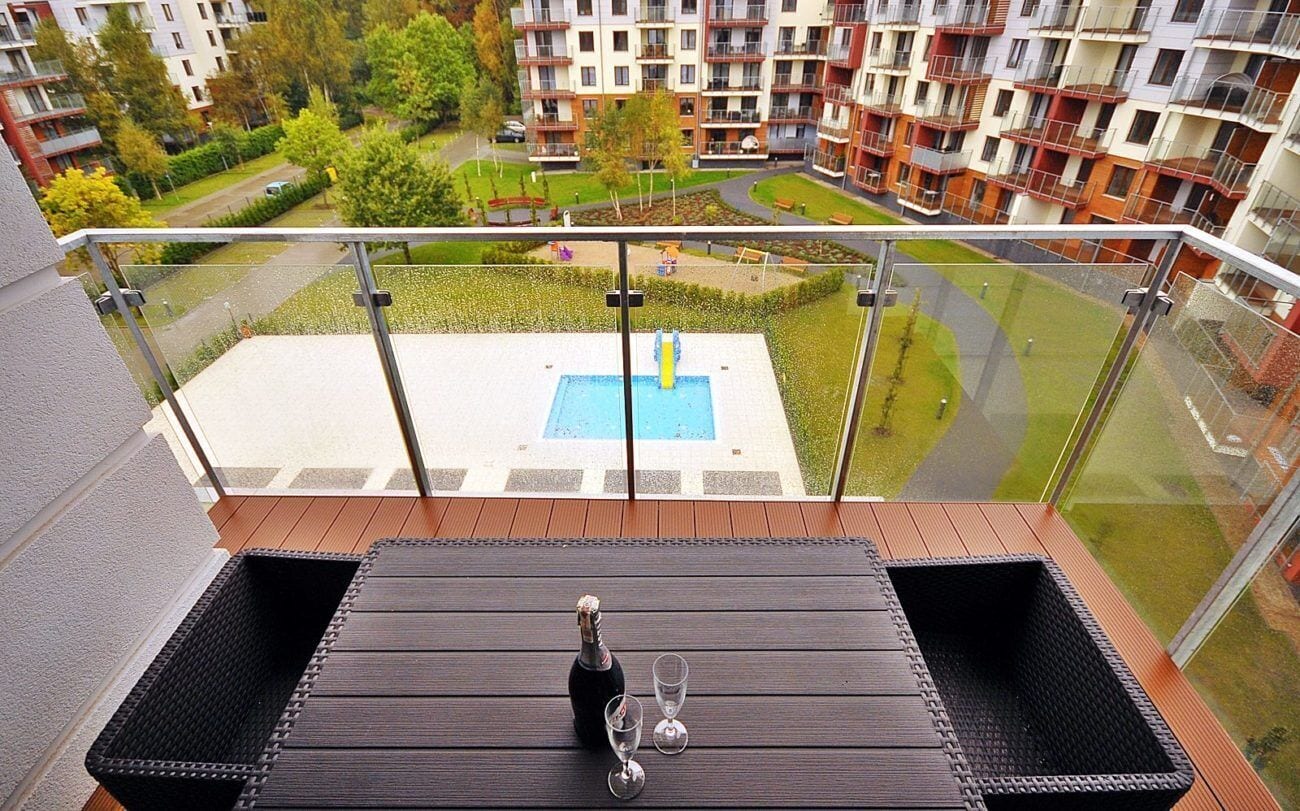 Uma varanda com vista para uma piscina, uma garrafa de champanhe e dois copos.