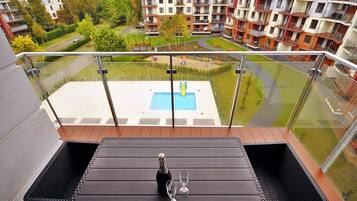 Uma varanda com vista para uma piscina, uma garrafa de champanhe e dois copos.